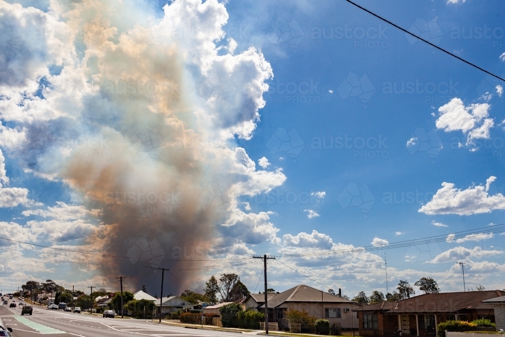 Image of Bushfire smoke billowing into sky behind houses along main ...