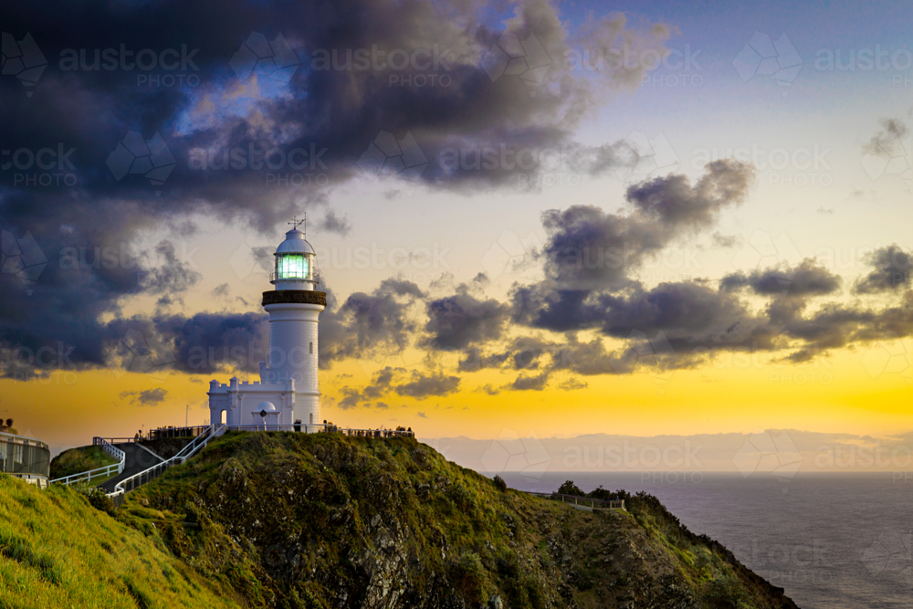 Image of Cape Byron Lighthouse glowing at sunset above the ocean cliffs ...