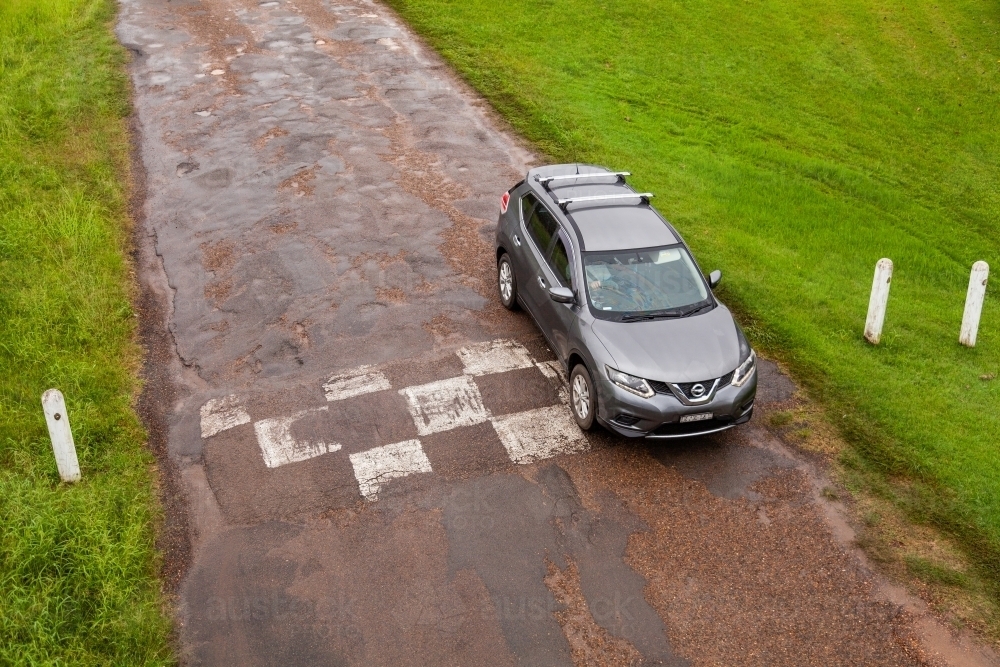 Image of car driving over speed bump on old patched road - Austockphoto