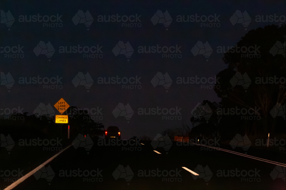 Image of car on country road late at night with left lane ends sign ...
