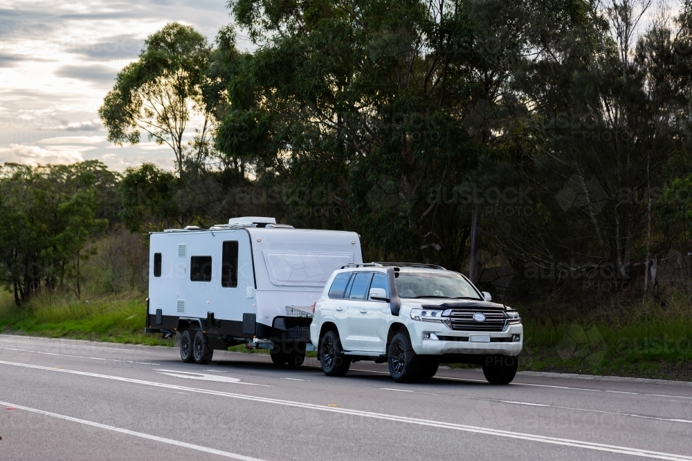 Image of car towing caravan on road at dusk - Austockphoto