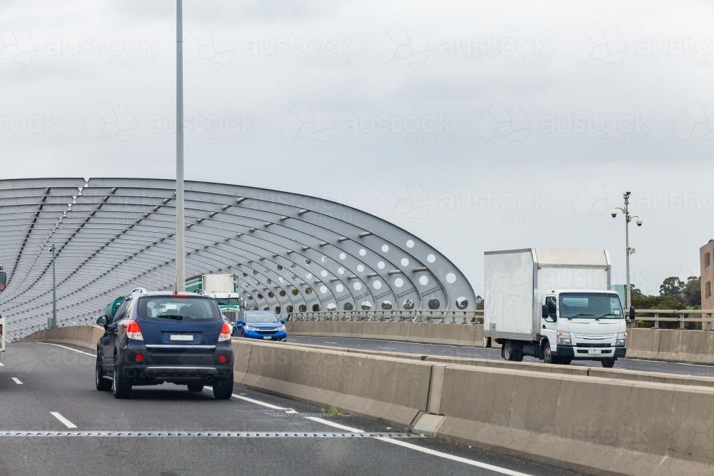 Image of Cars and trucks driving on bridge through melbourne - Austockphoto