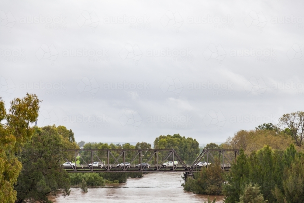 Image of Cars backed up on bridge over brown floodwaters of flooding ...