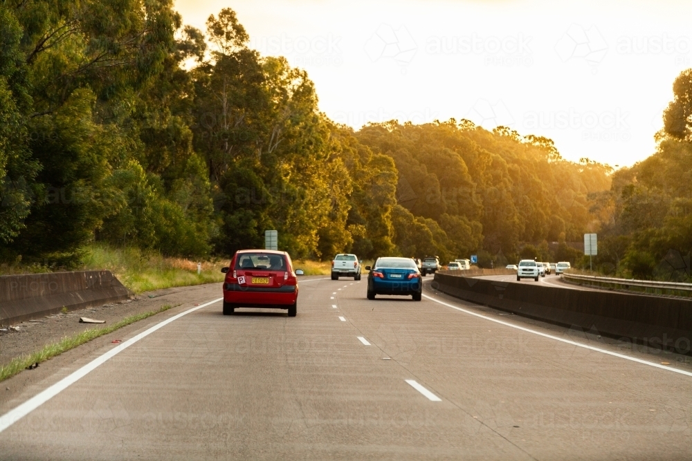 Image of Cars driving down highway road at sunset - Austockphoto