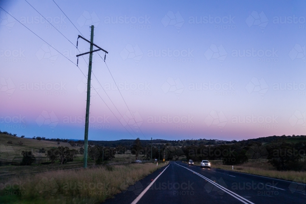 Image of Cars driving on country road at dusk with headlights on - low ...
