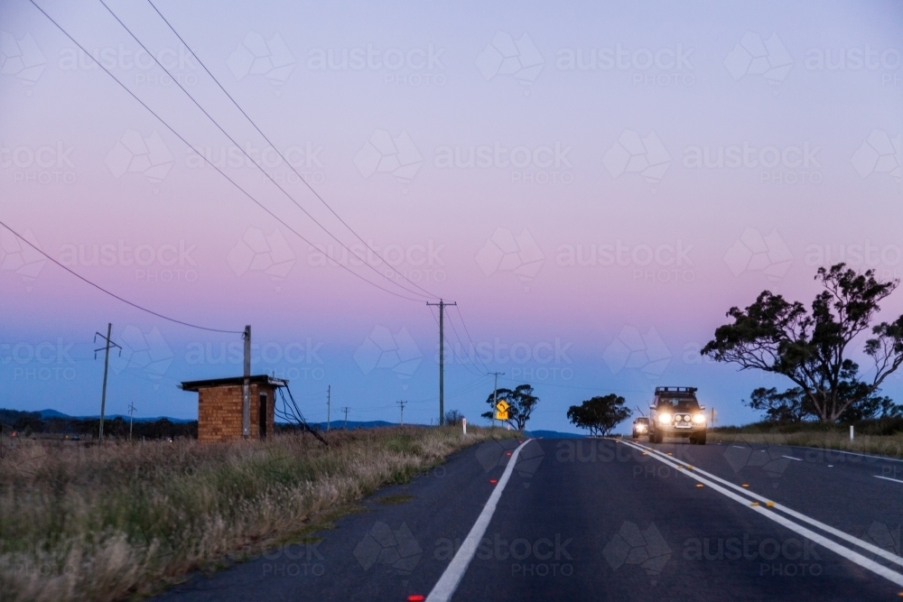 Image of Cars driving on country road at dusk with headlights on - low ...