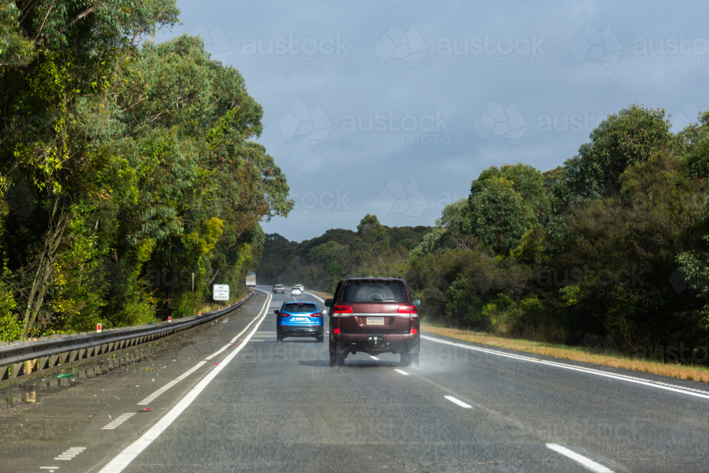Image of Cars on sunlit road after rainwater spray coming from tyres on ...