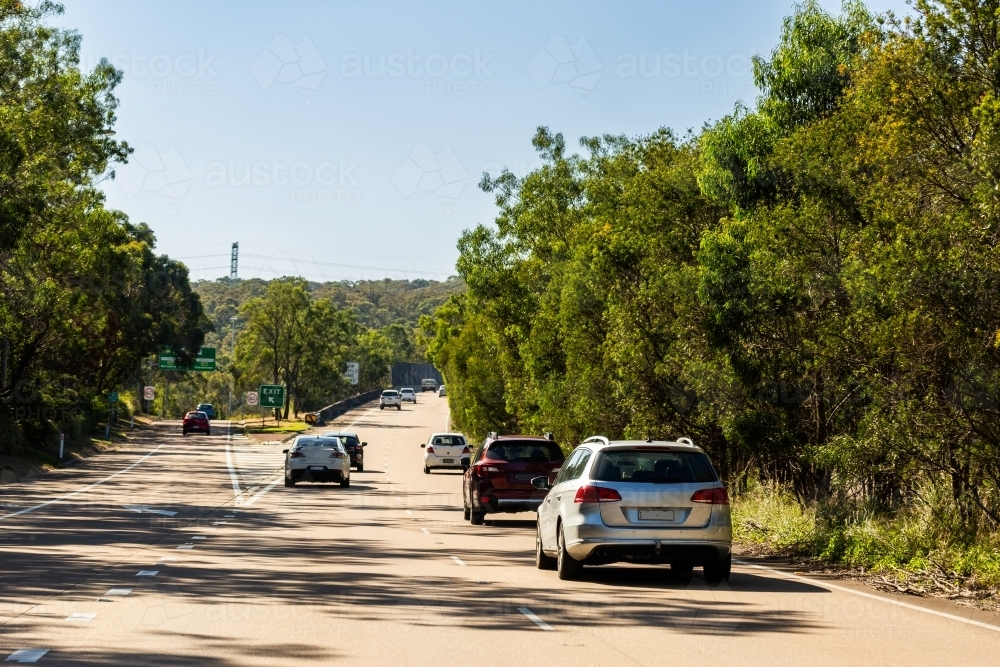 Image of Cars travelling on highway with exit to the left - Austockphoto