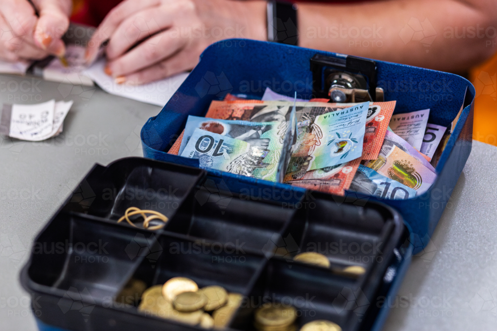 Image of Cash box with raffle ticket book on table and person selling ...