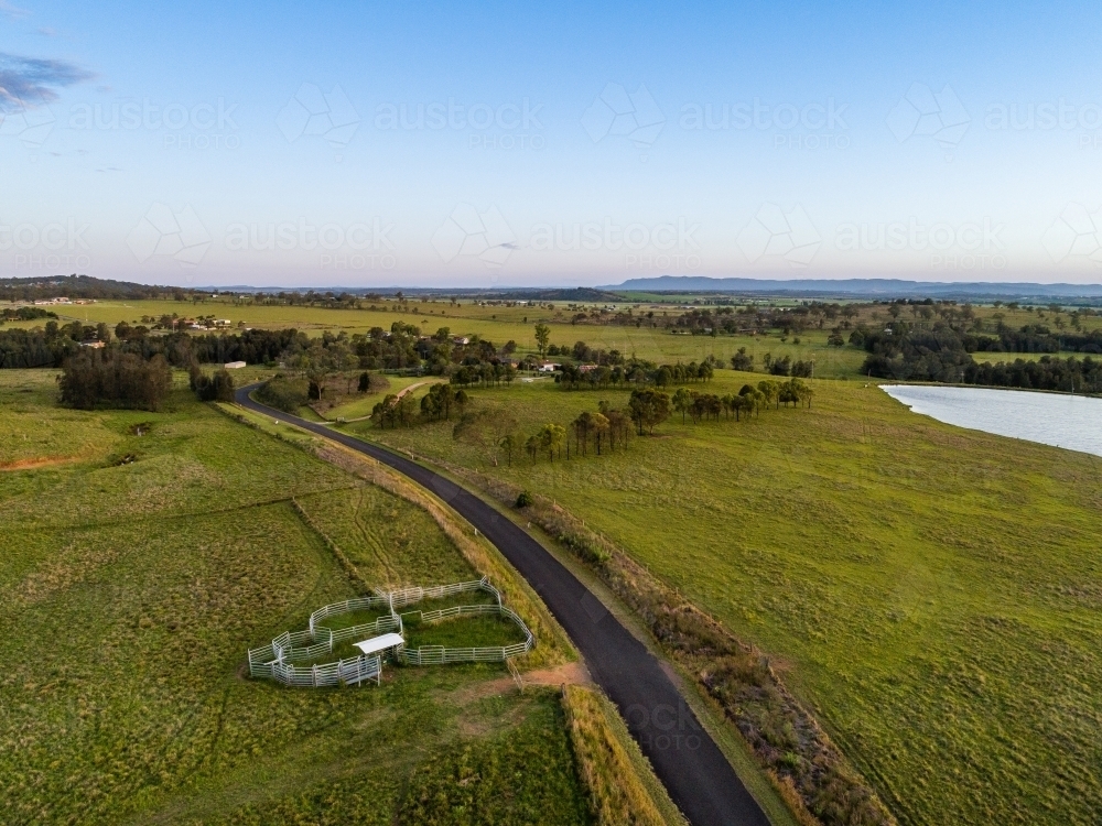 Image of Cattle yards and empty narrow country road at dusk - Austockphoto
