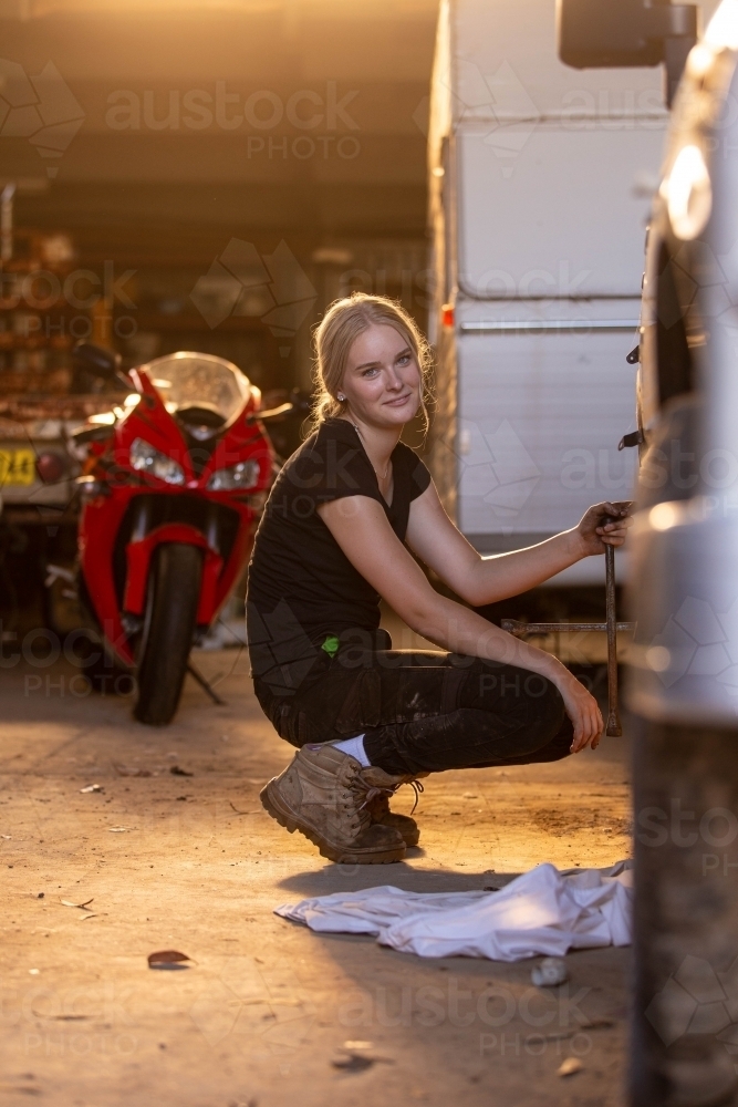 Image of Caucasian repairwoman working on fixing a car tyre in garage ...