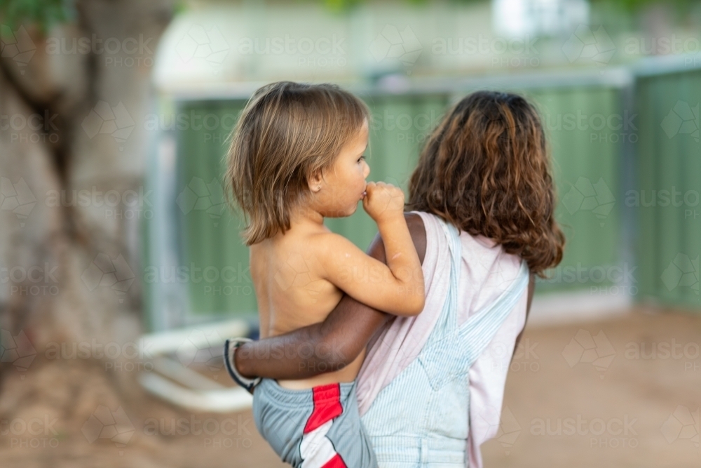 Image of child carrying toddler on her hip - Austockphoto