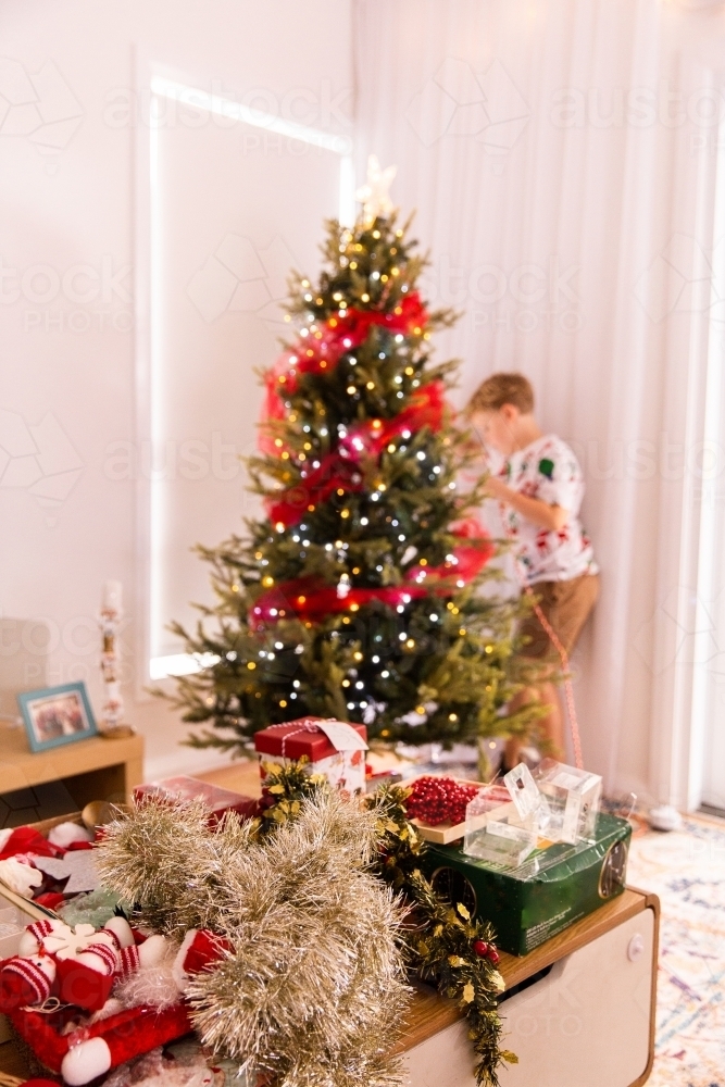 Image of child decorating a christmas tree in the lounge room focus on ...