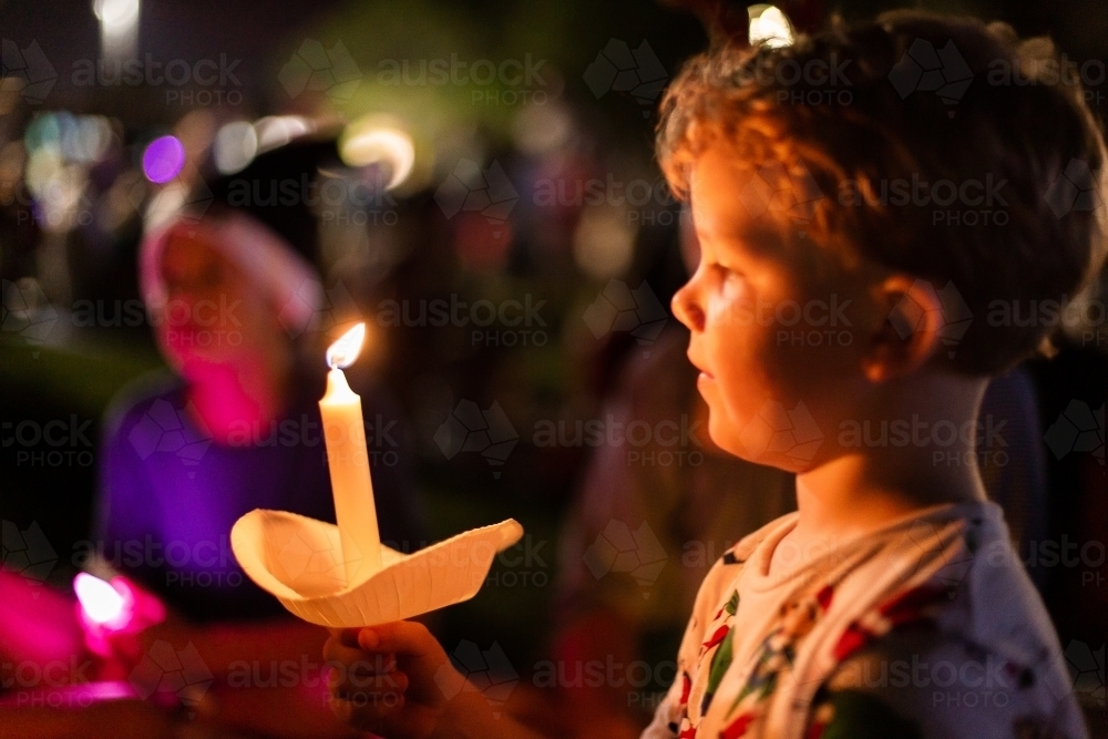 Image of child holding a candle at a carols event at night - Austockphoto
