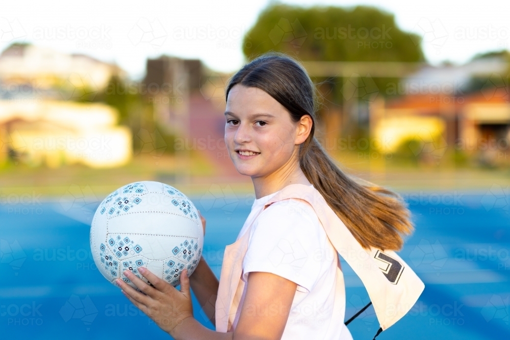 Image of child netball player in action with netball on blue outdoor ...