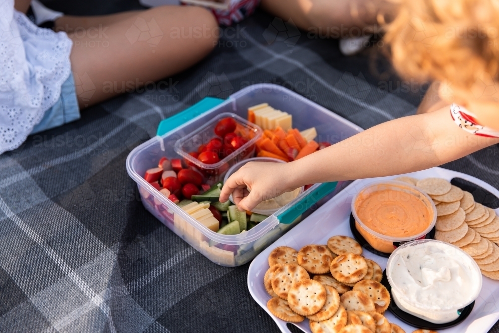 Image of child reaching for food on a picnic rug - Austockphoto