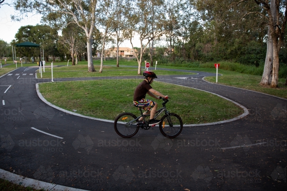 Image of child riding on a bike track learning road rules - Austockphoto