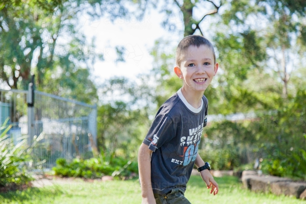 Image of Child running past smiling as he plays chase in rural backyard ...