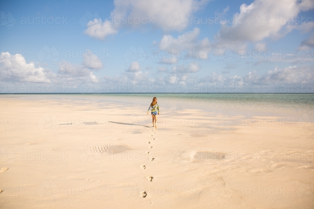 Image of child walking with single set of footprints on a beach ...