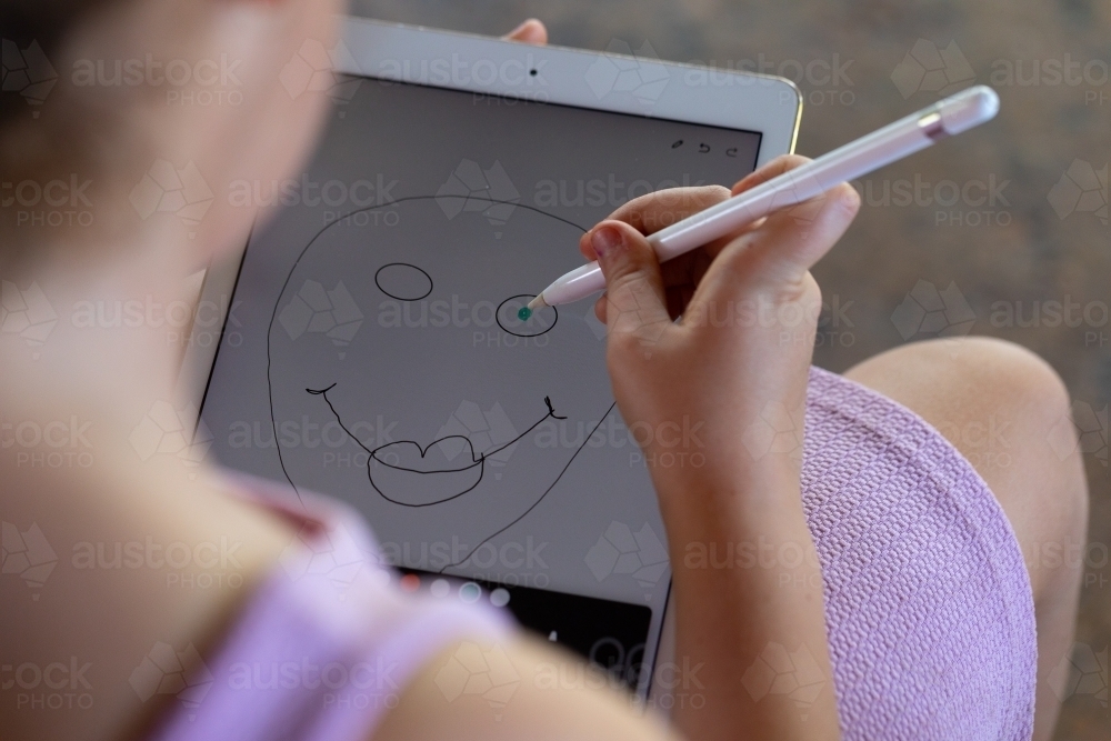 Image of child with awkward pencil grip drawing on digital tablet ...