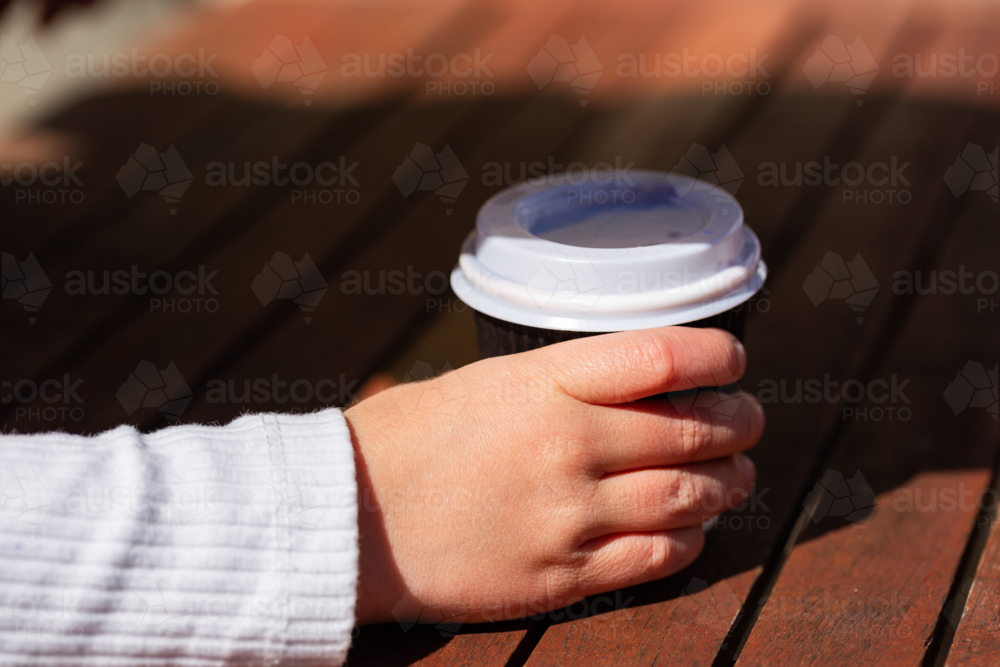 Image of Child with baby chino in takeaway cup on café table - Austockphoto