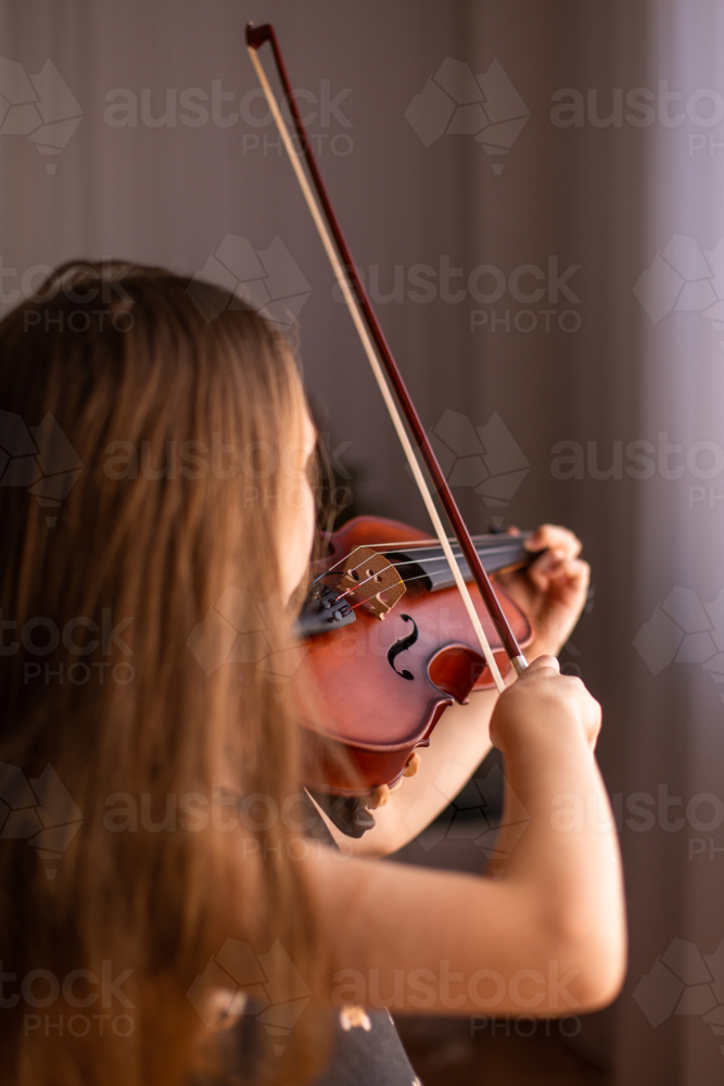 Image of child with long hair preparing to play the violin - Austockphoto