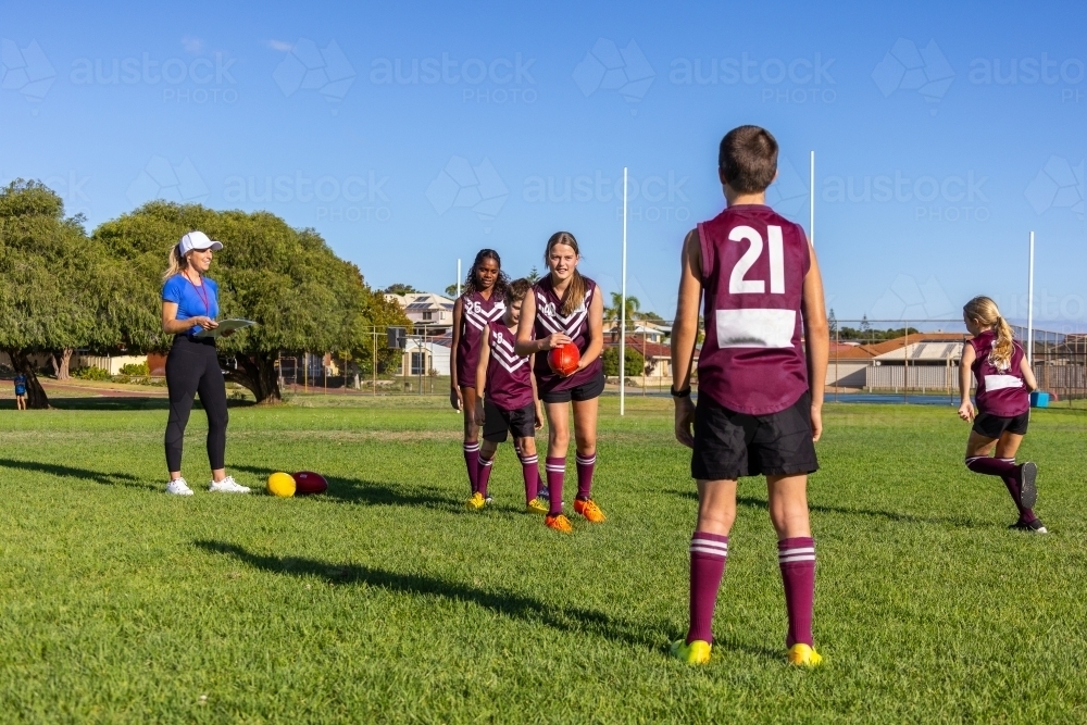 Image of children at football training with a female coach on green ...