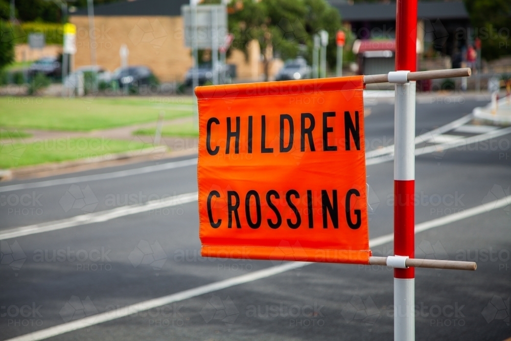 Image of Children crossing sign beside school - Austockphoto