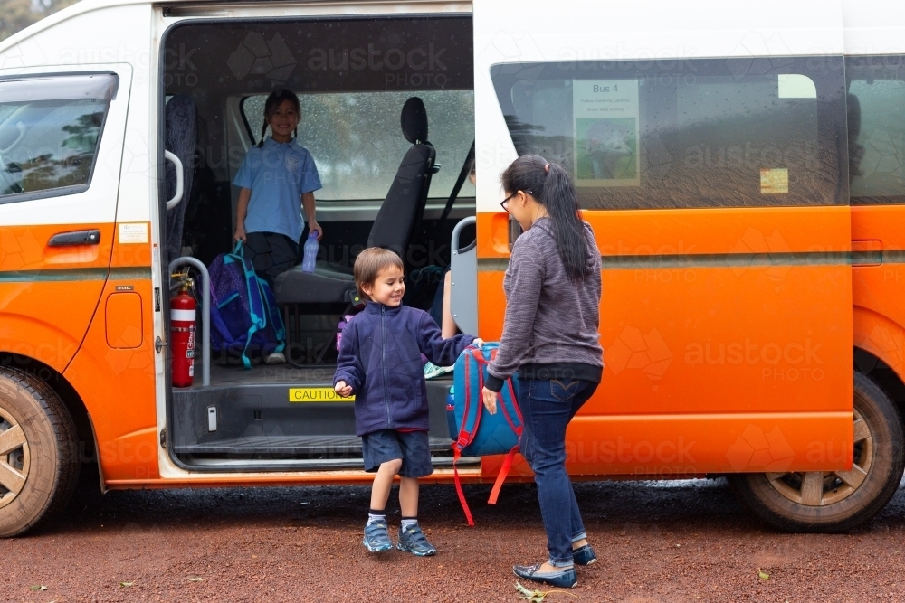 Image of Children getting of a school bus on gravel road - Austockphoto