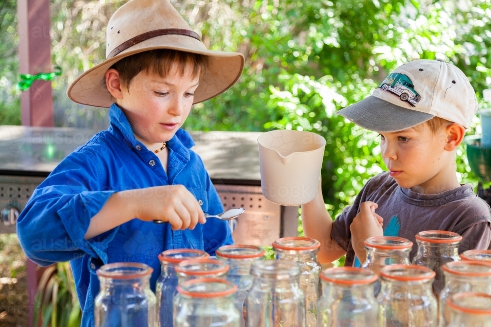 Image of Children helping with preserving fresh fruit in canning jars ...