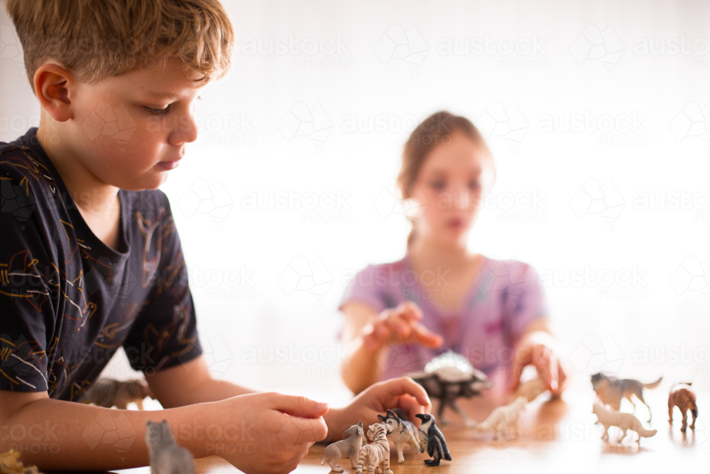 Image of children playing with animal toys on a table - Austockphoto