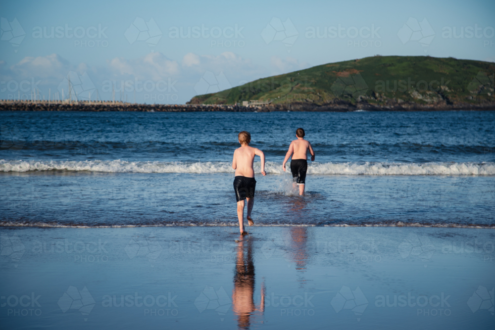 Image of Children running into rolling waves on the beach at Coffs ...