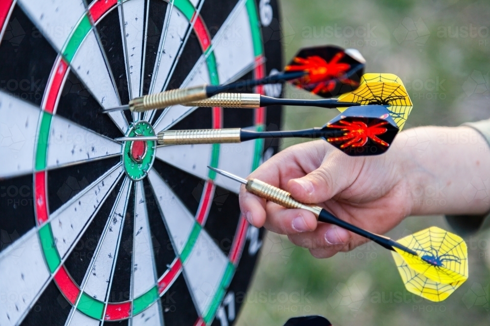 Image of Childs hand pulling throwing darts off dart board - Austockphoto