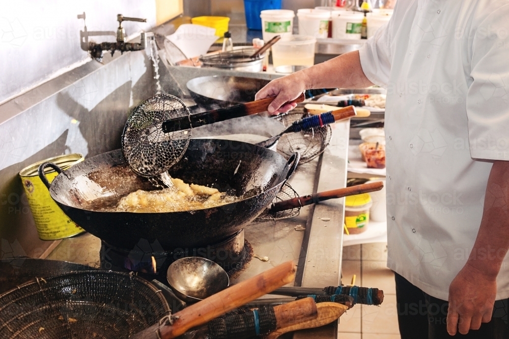 Image of chinese chef cooking in a busy commercial kitchen - Austockphoto