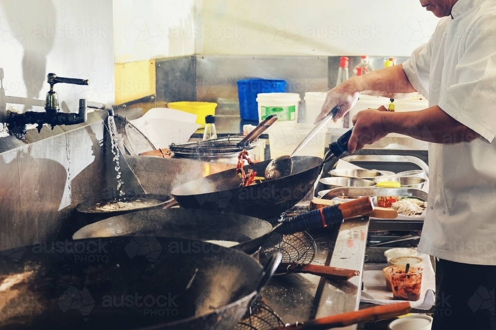 Image of chinese chef cooking in a busy commercial kitchen - Austockphoto