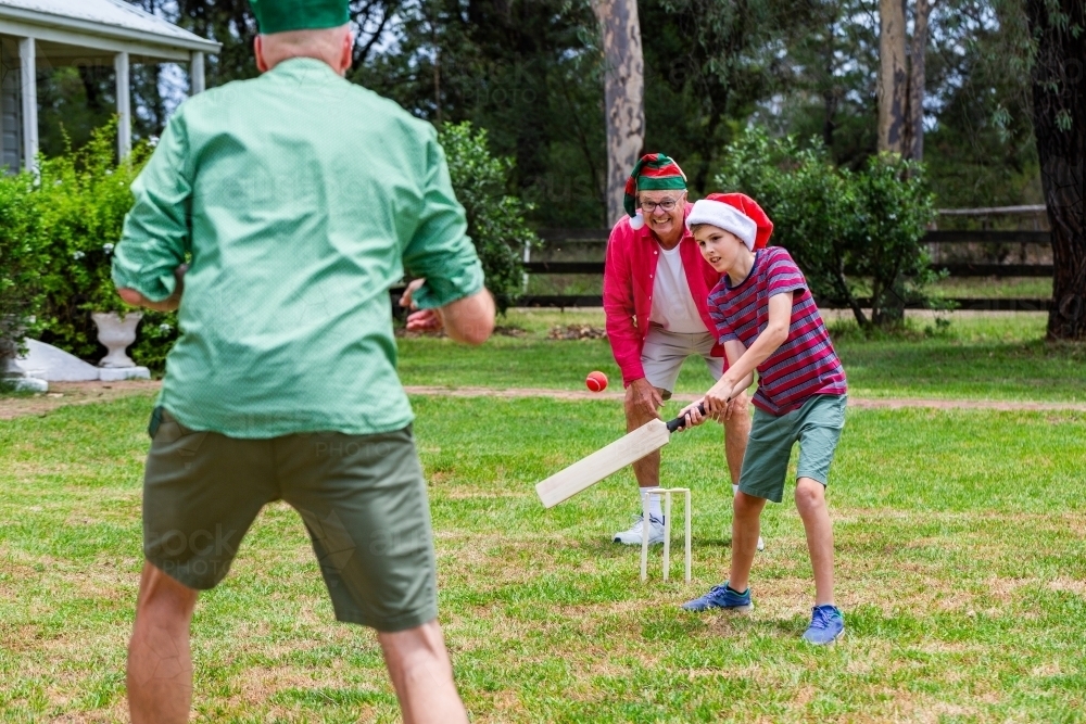 Image of Christmastime backyard cricket game with boy hitting ball ...