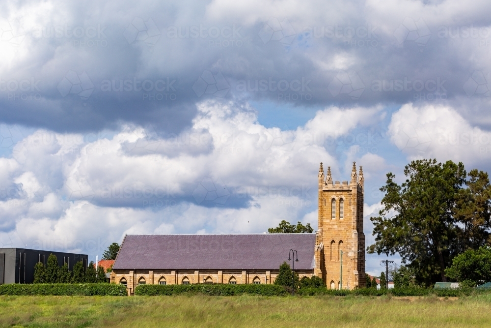 Image of Church building seen over levee bank with clouds overhead ...
