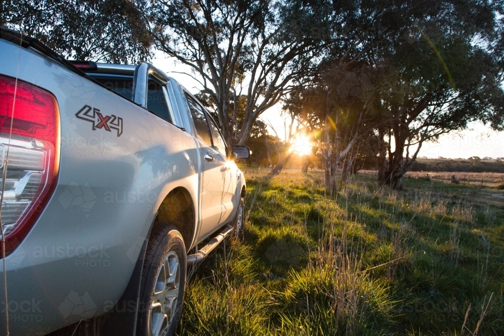 Image of Close up of a 4WD vehicle with sun flare and bush at sunset ...