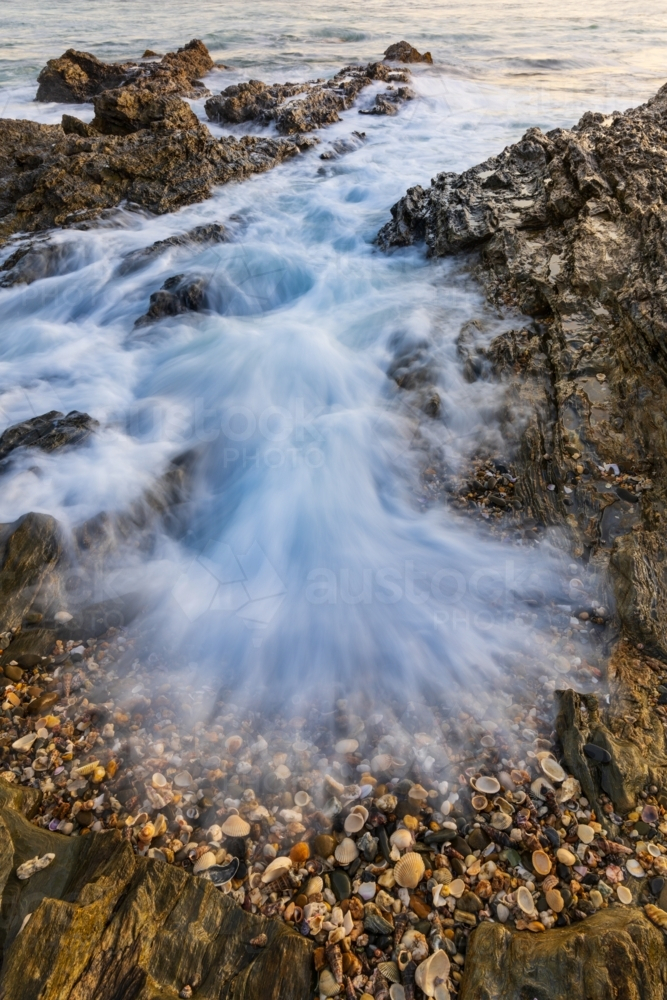 Image of Close up of a waves splashing into a rockpool covering a ...