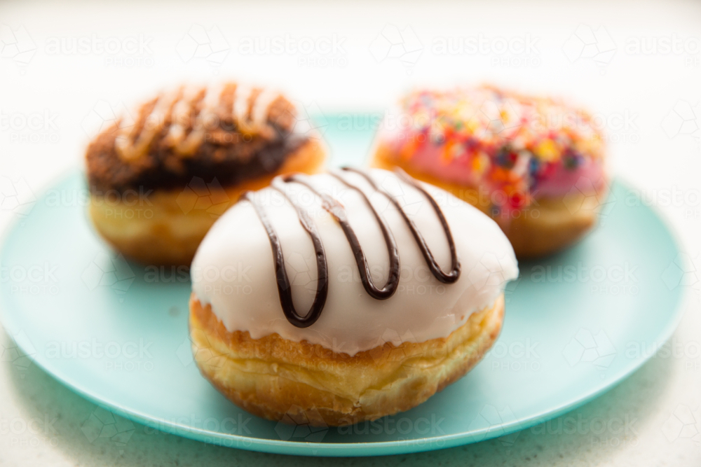 Image of close up of an iced doughnut with others behind - Austockphoto