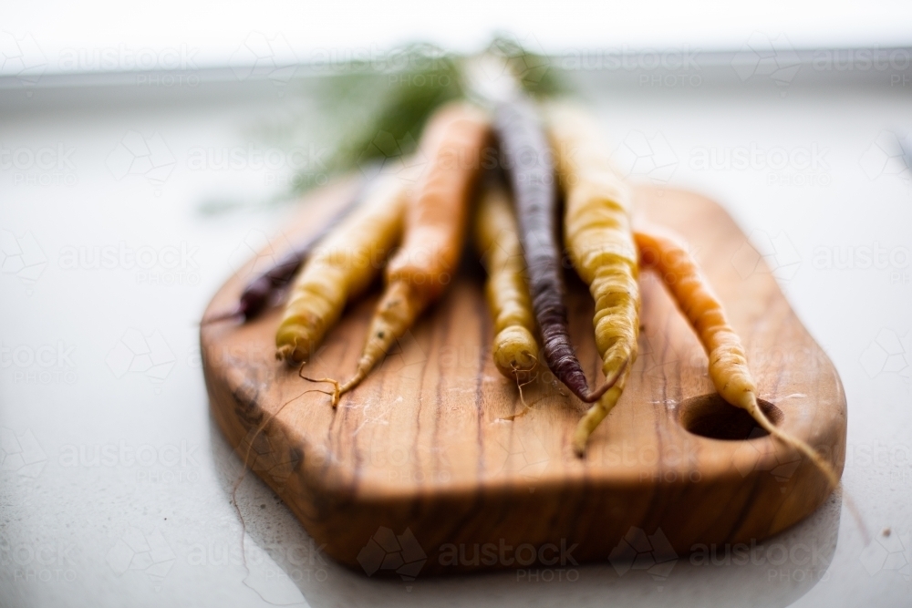 Image of close up of carrot tips on a wooden chopping board - Austockphoto