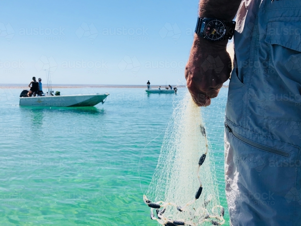 Image of close up of mans hand holding fishing throw net on clear aqua ...