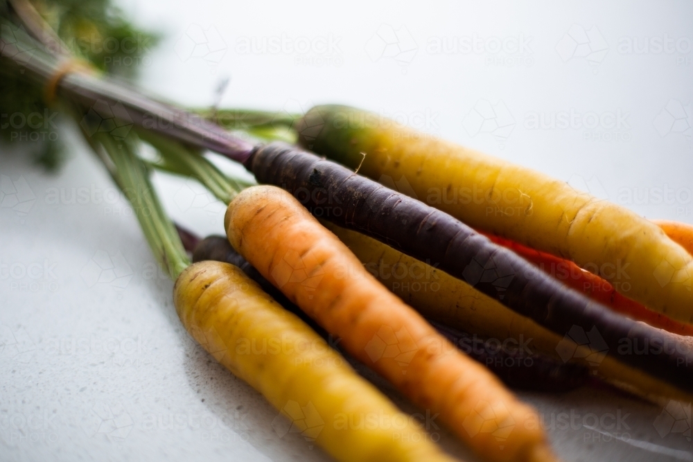 Image of close up of rainbow carrots on a kitchen bench - Austockphoto