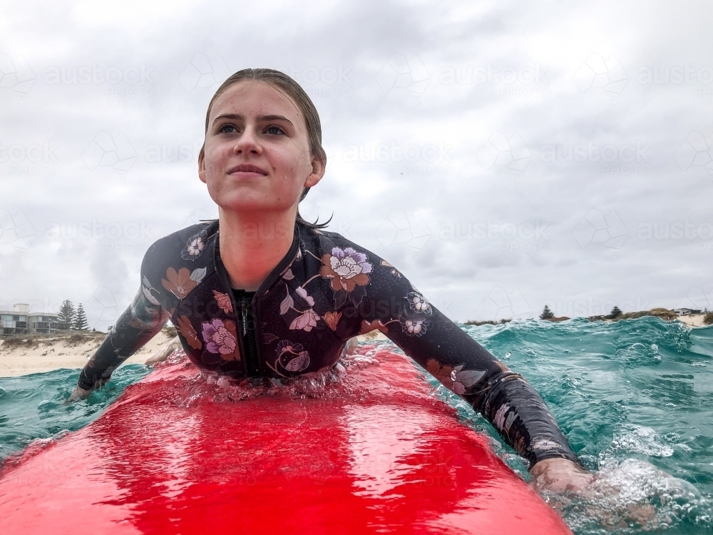Image of Close up of Teenage girl paddling red surfboard on ocean with ...