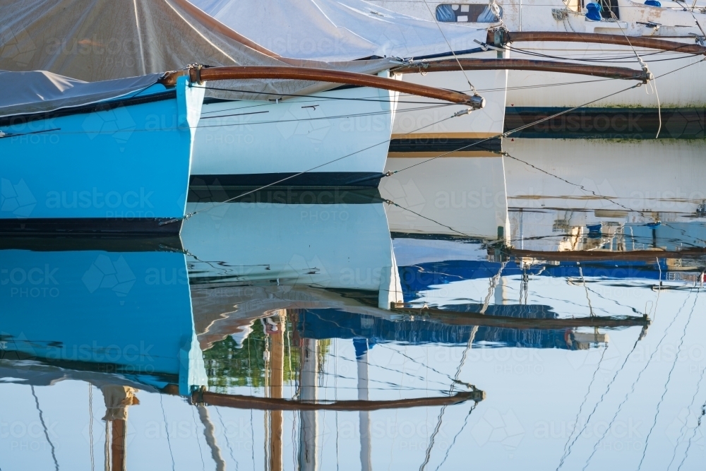 Image of Close up reflections of colourful couta boat hulls on still ...