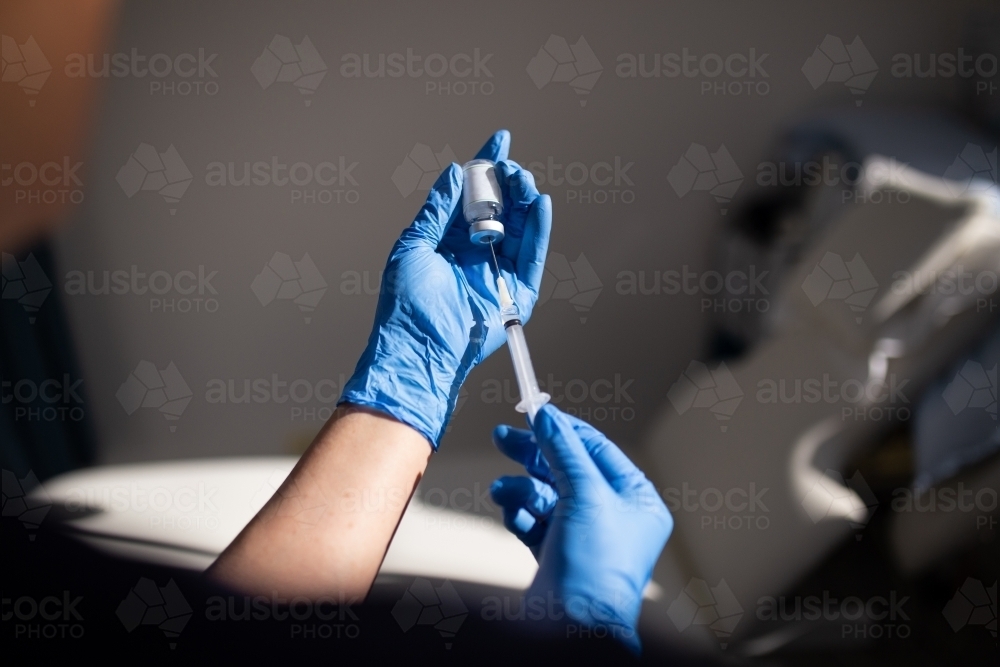 Image of Close up shot of a syringe being inserted to a medicine glass ...