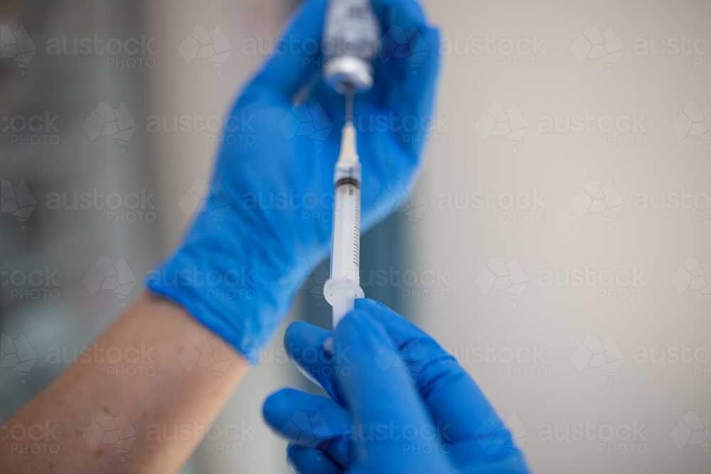 Image of Close up shot of a syringe being inserted to a medicine glass ...