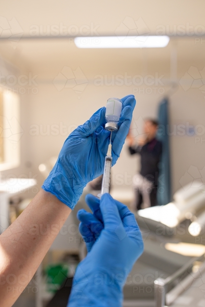 Image of Close up shot of a syringe being inserted to a medicine glass ...