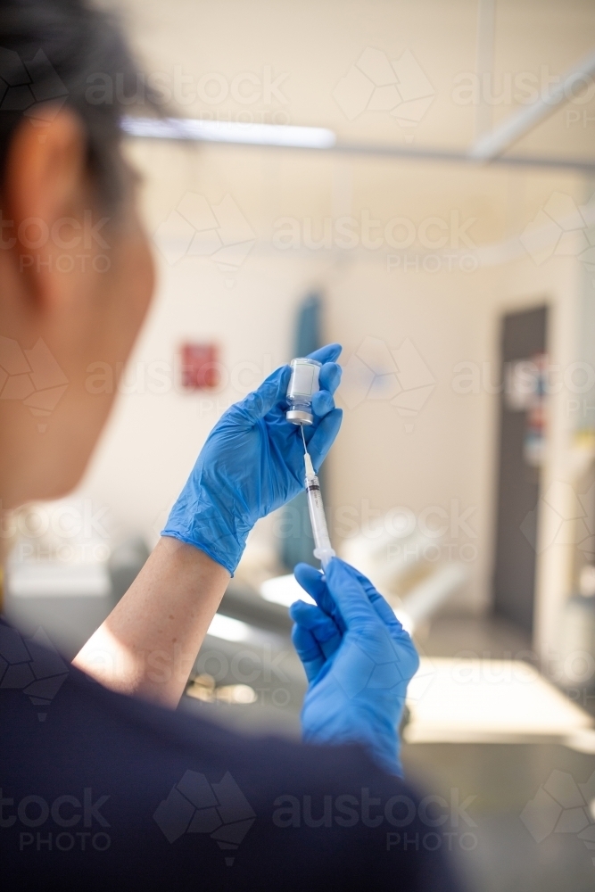 Image of Close up shot of a syringe being inserted to a medicine glass ...