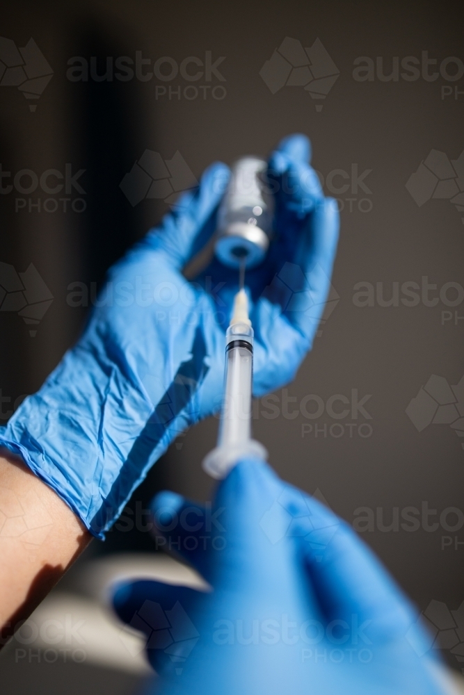 Image of Close up shot of a syringe being inserted to a medicine glass ...